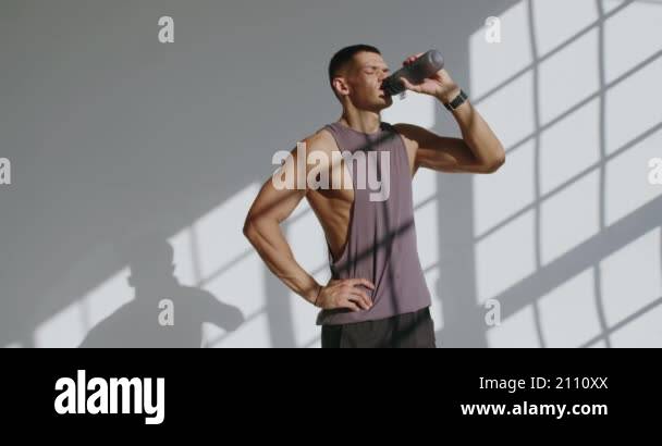 A 23-year-old man with an athletic physique sipping water during a ...