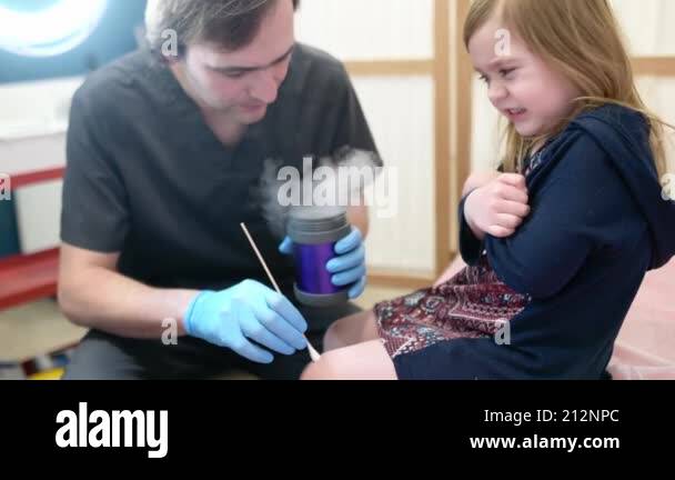 A caring doctor checks moles and warts on the skin of a small child ...