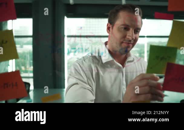 Professional male leader writing marketing idea on sticky notes ...