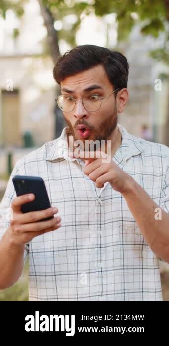Oh my God, Wow. Excited happy joyful winner young man using smartphone ...