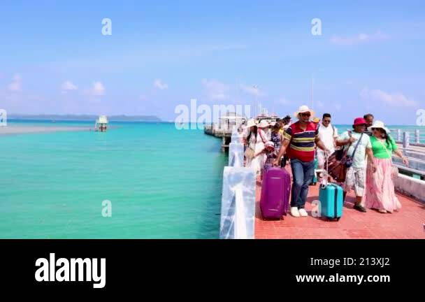 passengers walking out from cruise ship at island jetty in afternoon ...