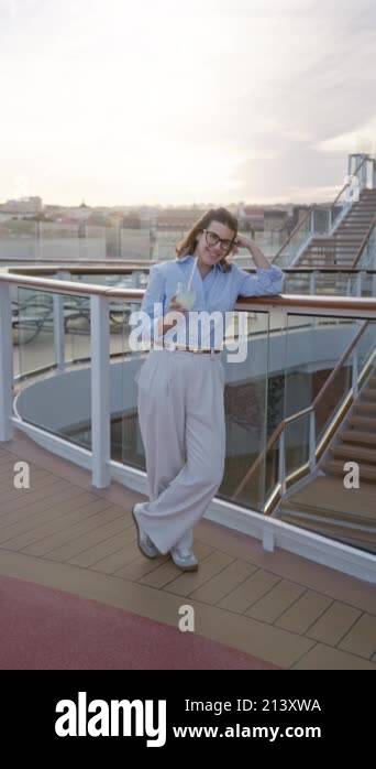 Woman enjoying drink outdoors on cruise ship deck at sunset with ...
