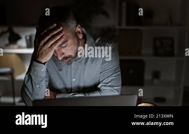 A mature bearded man with grey hair looking stressed and thoughtful at ...
