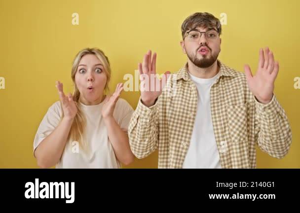 Shocked beautiful couple, mouths agape in disbelief, stand isolated on ...