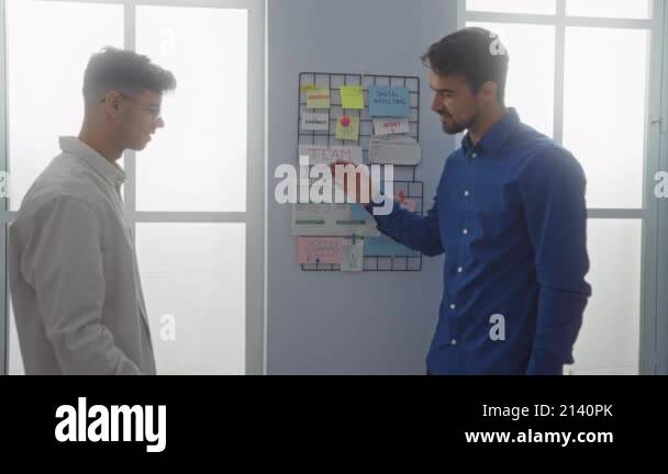 Hispanic men in business attire engage in a friendly handshake in a ...