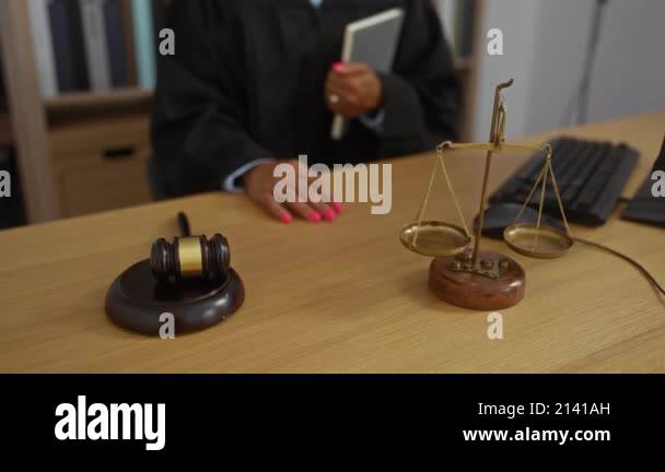 Woman judge reaching for gavel in office with scales of justice and ...