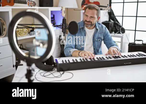 Handsome mature man playing keyboard in music studio with microphone ...