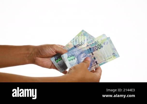 Hands holding and counting multiple south african rand currency notes ...