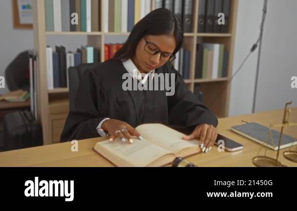 Woman studying in an office, wearing judicial robes and reading a book ...