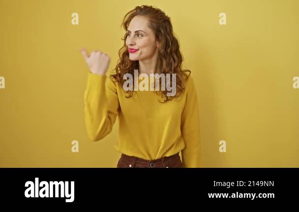 Cheerful young woman confidently pointing thumb up with a beaming open ...