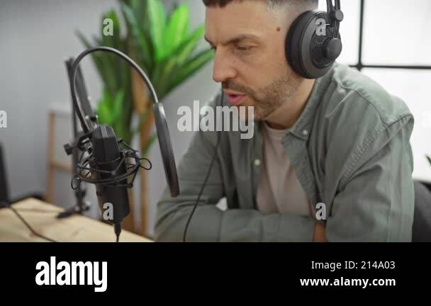 Handsome man with beard recording audio in modern radio studio, wearing ...