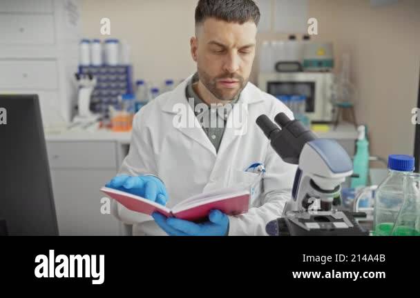 Hispanic scientist man with beard reviewing notes and using microscope ...