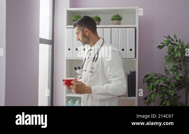 Hispanic male doctor in a hospital office drinking coffee, with medical ...