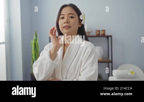 Chinese woman in a spa, wearing a white robe and a flower in her hair ...