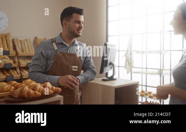 Baker talking to woman customer at bakery shop counter indoors with ...