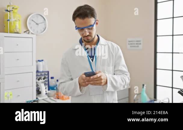 Hispanic male scientist with glasses using smartphone in laboratory ...