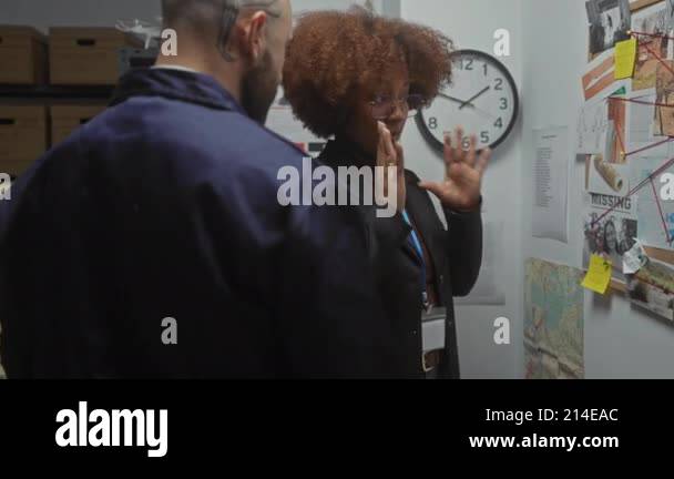 A man and a woman discuss evidence in a cluttered investigation office ...
