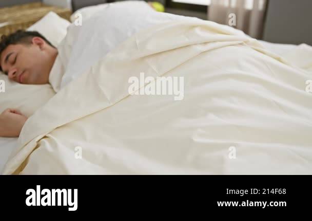 A young man waking up stretching in a cozy modern bedroom with natural light Stock Video Footage ...