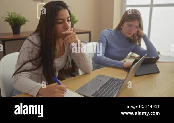 Two women focused and multitasking in a modern home office, one ...