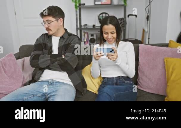 A man looking skeptically at a smiling woman engrossed in her ...