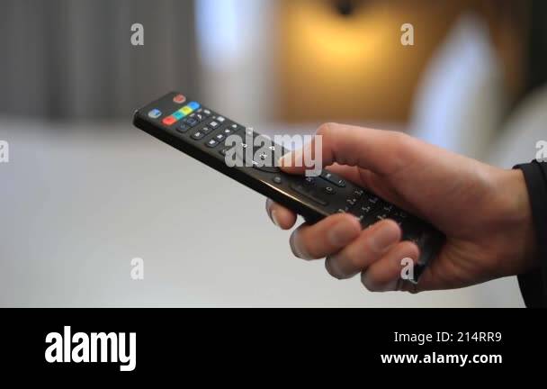 Person hand grips remote control in stylish living room with soft ...