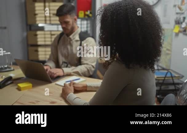 Man and woman collaborate in a cluttered office, indicative of ...