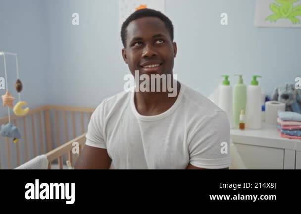 Handsome man smiling in a cozy bedroom with a wooden cradle and baby ...