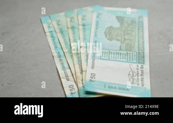 Indian fifty rupee banknotes displayed on a concrete surface depict ...
