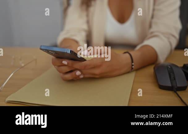 Woman browsing phone in office setting with a mouse on desk, showing ...