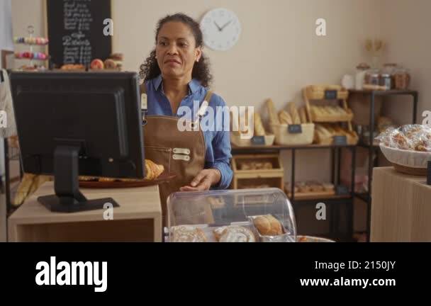 Woman working in bakery shop, serving customer fresh pastries, standing ...