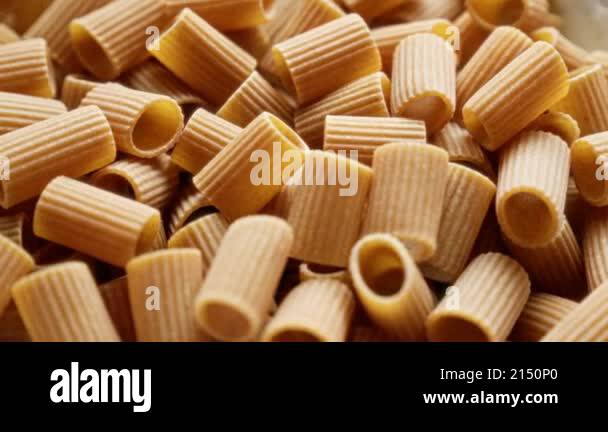 Closeup of uncooked brown pasta tubes stacked, showcasing texture ...