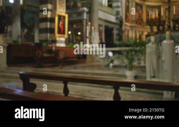 Blurred view of an ornate church interior with pews, religious artwork ...