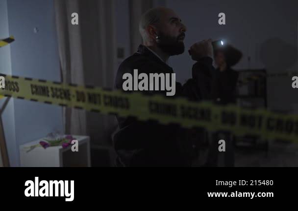 A man and a woman, possibly detectives, investigate an indoor crime ...