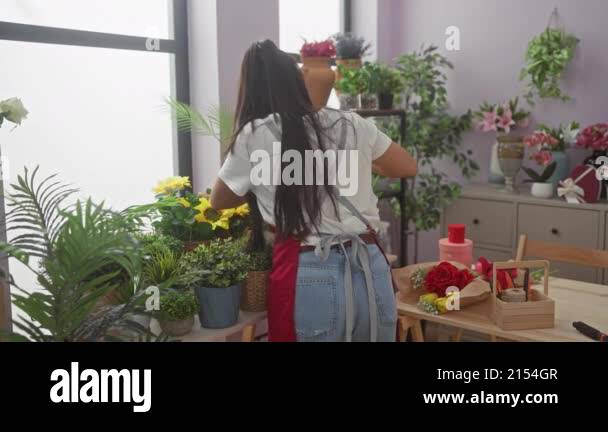 Two women engage in a friendly handshake at a flower shop filled with ...
