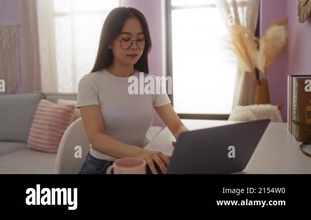 Woman typing on laptop in living room, closing it, and relaxing ...