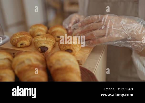 Woman packaging freshly baked pastries in a bakery with gloved hands ...