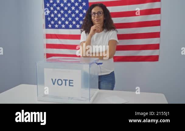 American middle age hispanic woman standing by vote ballot, pointing ...