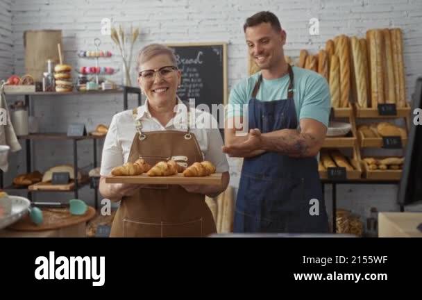 Woman and man bakers in a bakery, holding croissants, smiling, man ...