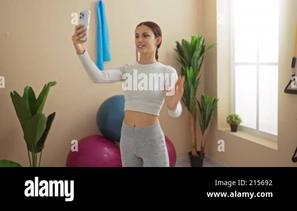 Female taking a self-portrait during a video call in a gym, surrounded ... Female taking a self-portrait during a video call in a gym, surrounded ...