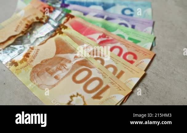 Canadian banknotes in various denominations are spread out on a ...