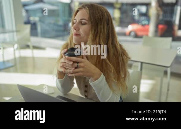 Woman enjoying coffee in a modern office environment with natural light ...