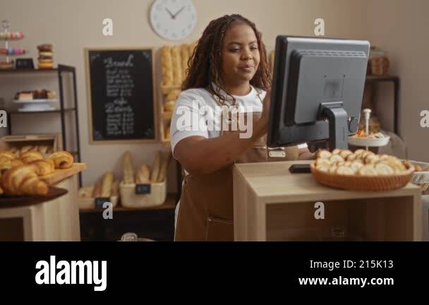 Woman working in a bakery room indoors, engaging with a computer ...