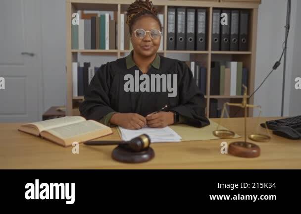 Woman judge smiling at desk in courtroom with gavel books and scales of ...