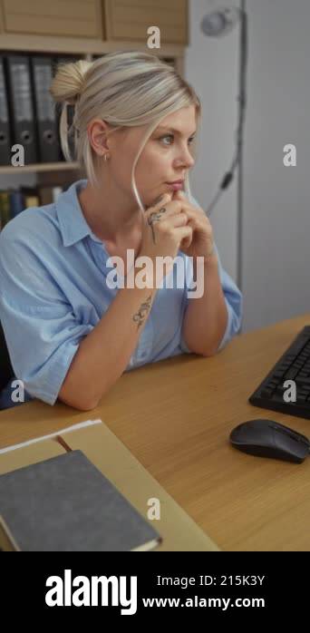 Young woman with tattoos working at office desk in a modern workplace ...