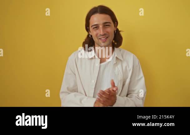 Young man clapping in front of isolated yellow background wearing ...
