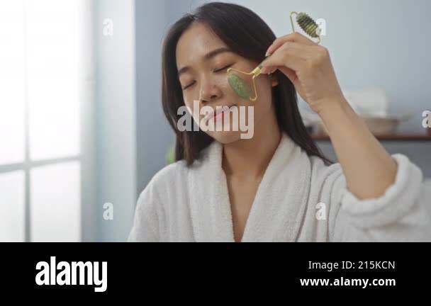 Woman using facial roller in spa room showcasing wellness routine with ...