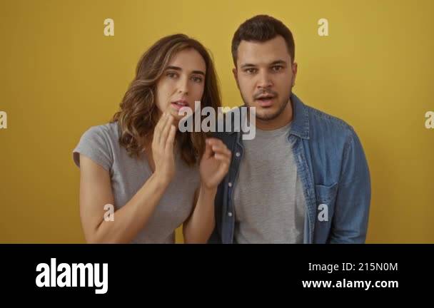 Man and woman posing together against yellow background displaying ...
