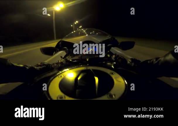 Male motorcyclist riding on modern sport bike in illuminated city empty ...