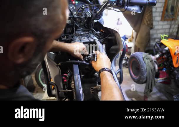 Professional mechanic repairing detail of motorcycle at workplace. Male ...