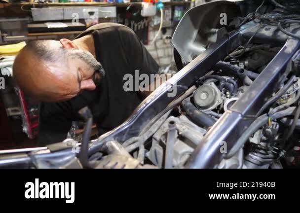 Professional mechanic repairing engine of motorcycle at workshop. Male ...